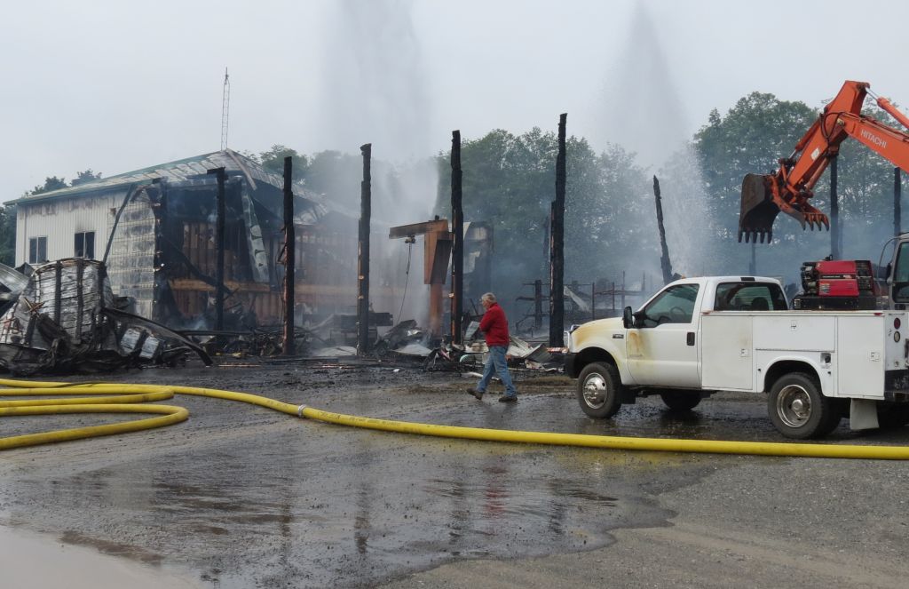 Owner John Friberg walks past as crews clean up following a fire that ...